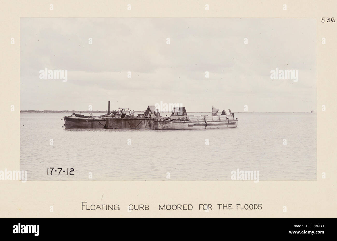 The photograph shows a floating curb being moored in preparation for ...
