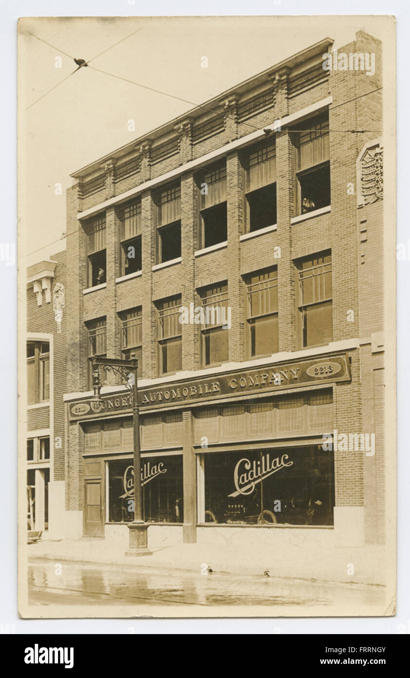 The photograph shows a Cadillac dealership, showcasing automobiles and ...