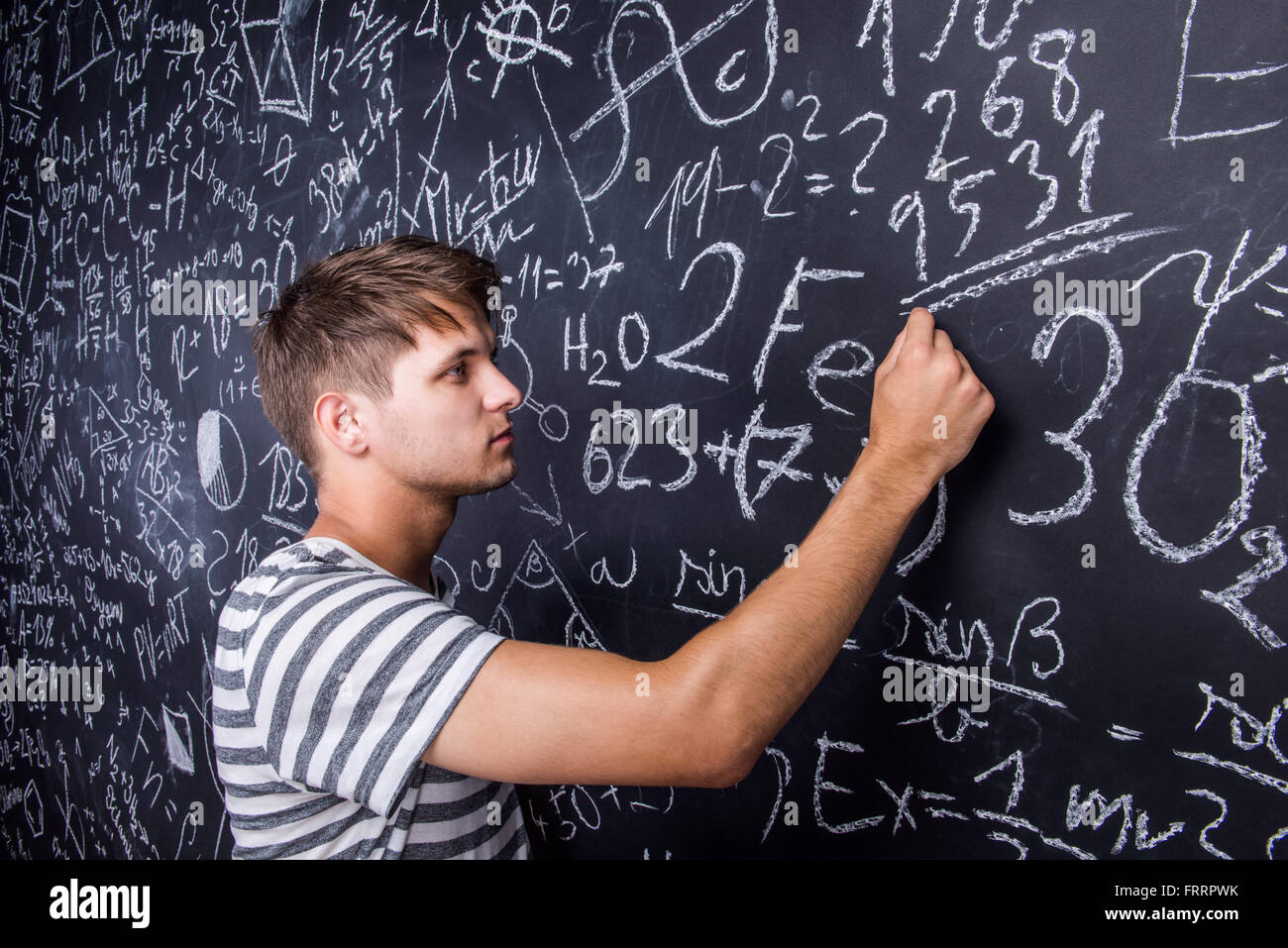 Student writing on big blackboard with mathematical symbols Stock Photo ...