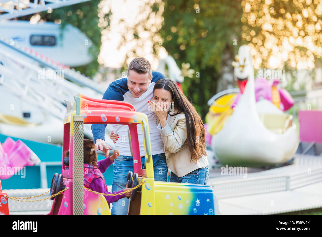 Parents at fun fair, waving their child taking ride Stock Photo - Alamy
