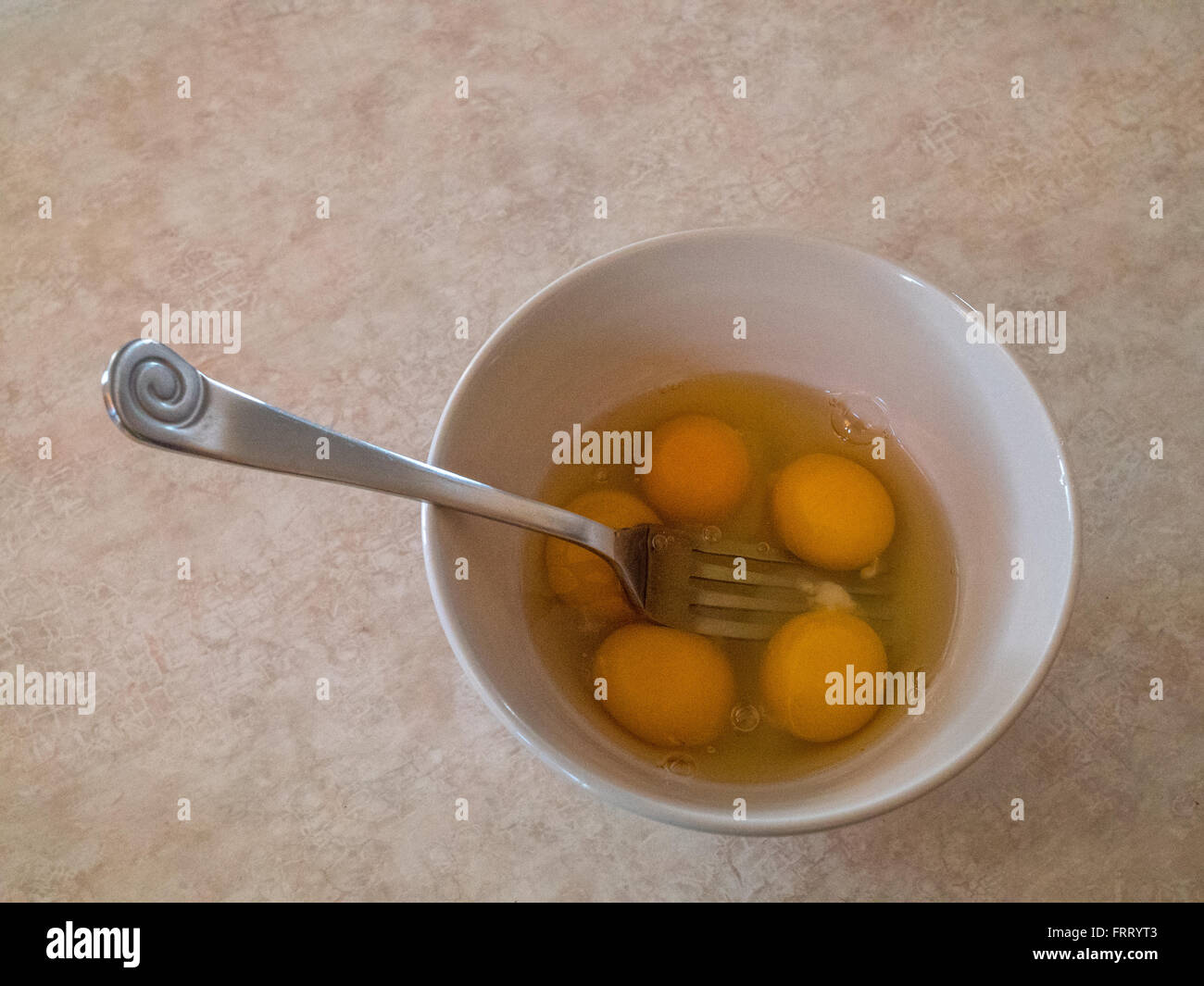 Intact raw eggs in white bowl with fork Stock Photo - Alamy
