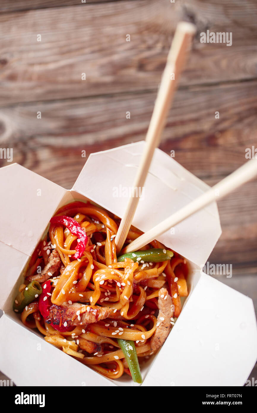 Noodles with pork and vegetables in take-out box on wooden table Stock ...