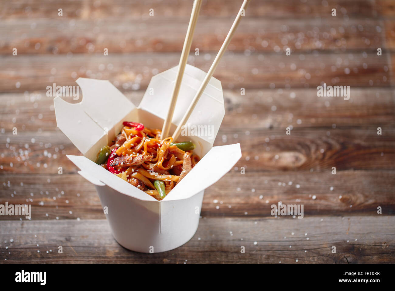 Noodles with pork and vegetables in take-out box on wooden table Stock ...