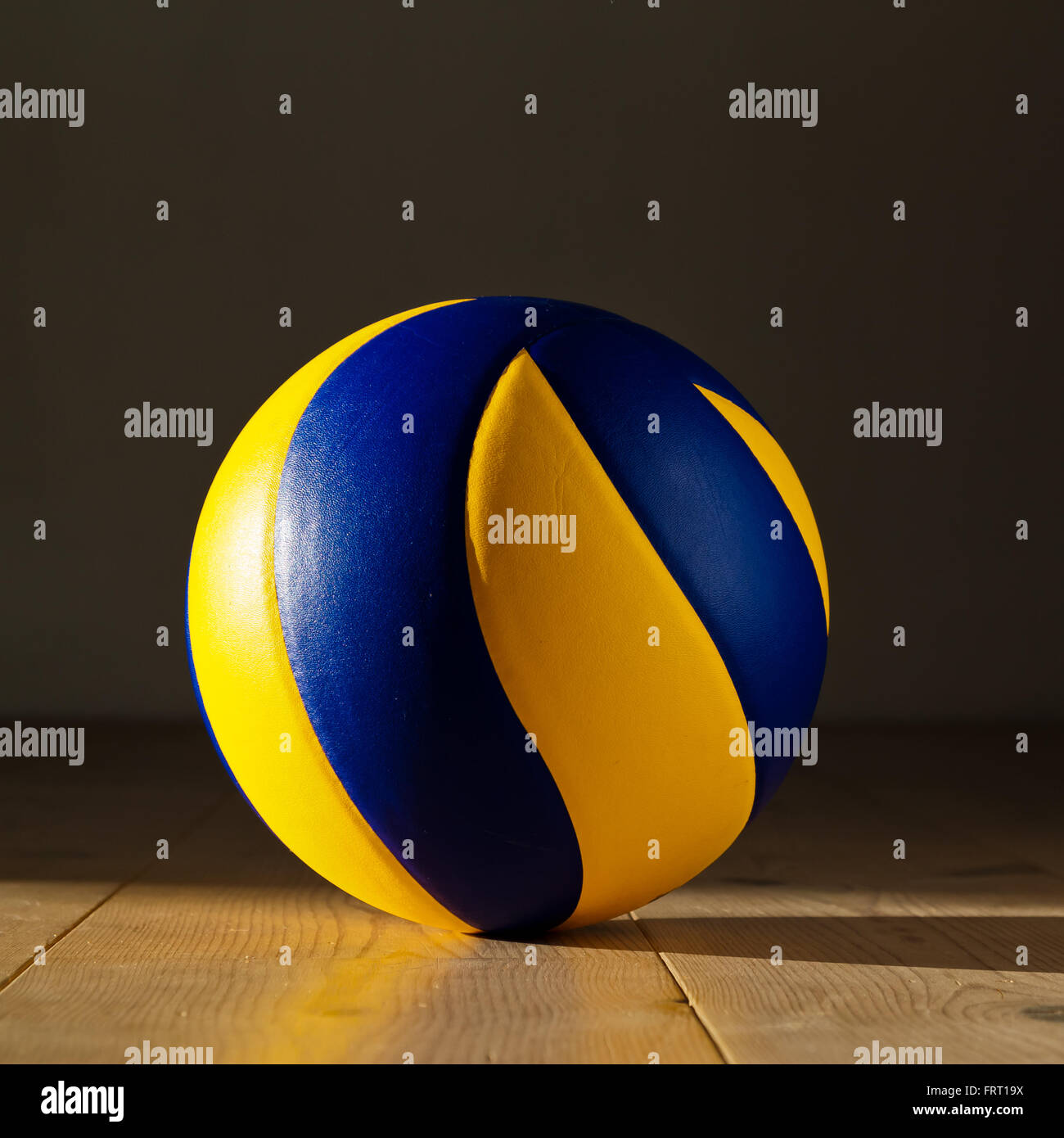 Soft blue and yellow ball lying on a wooden floor in the sun, ready to ...