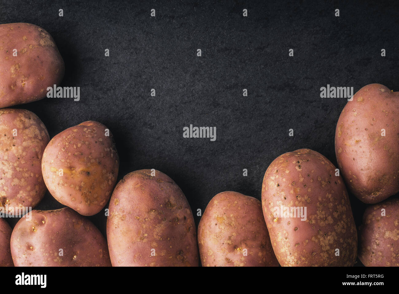Raw potatoes on the black stone table Stock Photo - Alamy