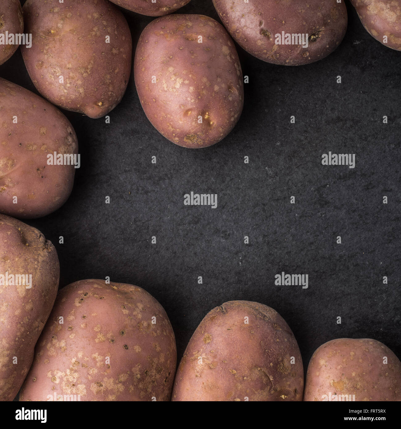 Raw potatoes at the left of the black stone table square Stock Photo ...