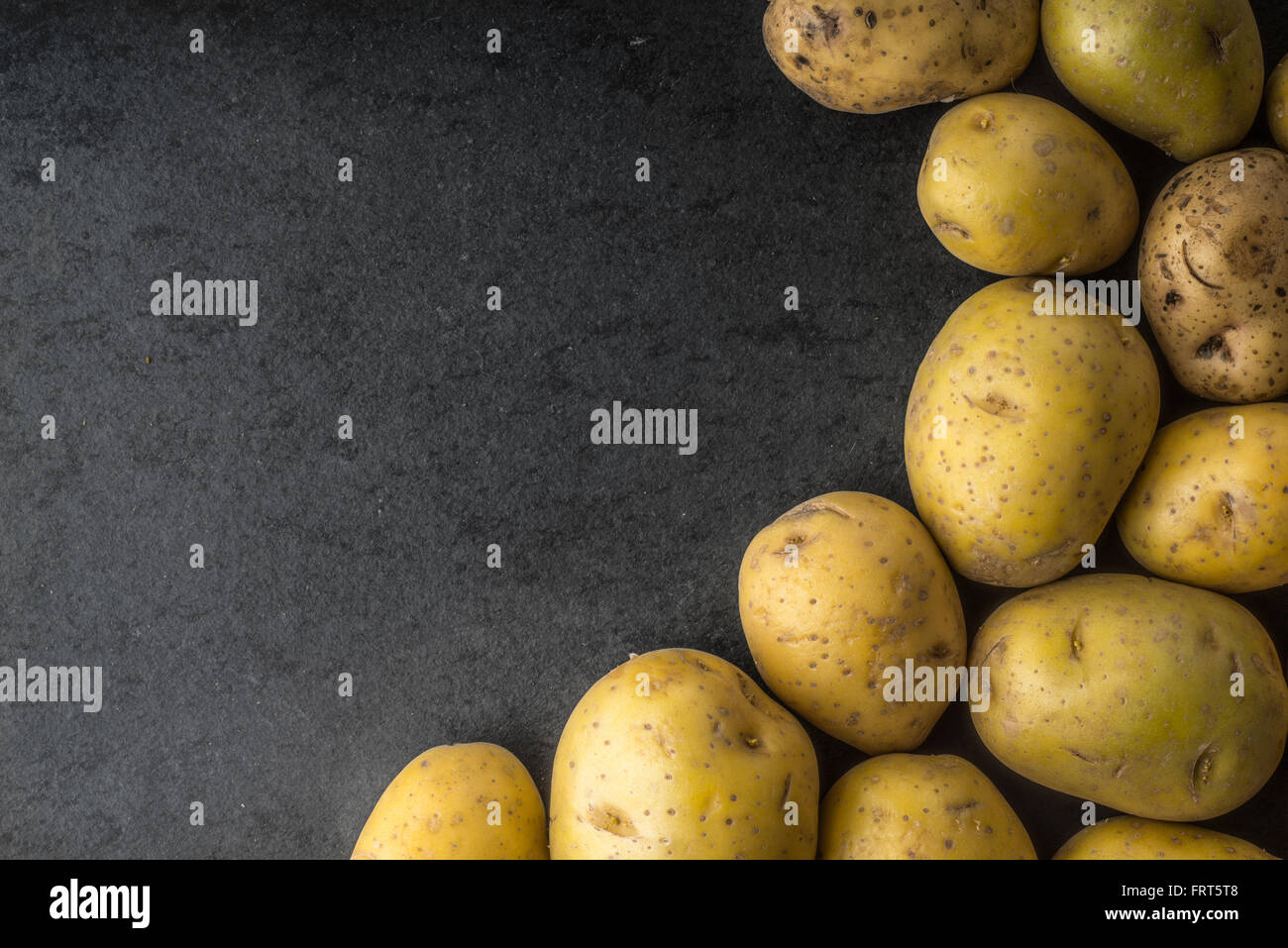 Raw potatoes on the black stone table top view Stock Photo - Alamy