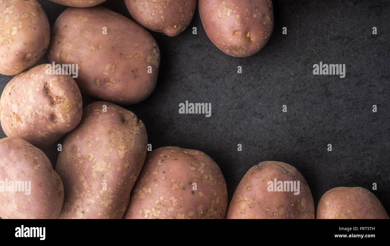 Raw potatoes on the dark stone table horizontal Stock Photo - Alamy