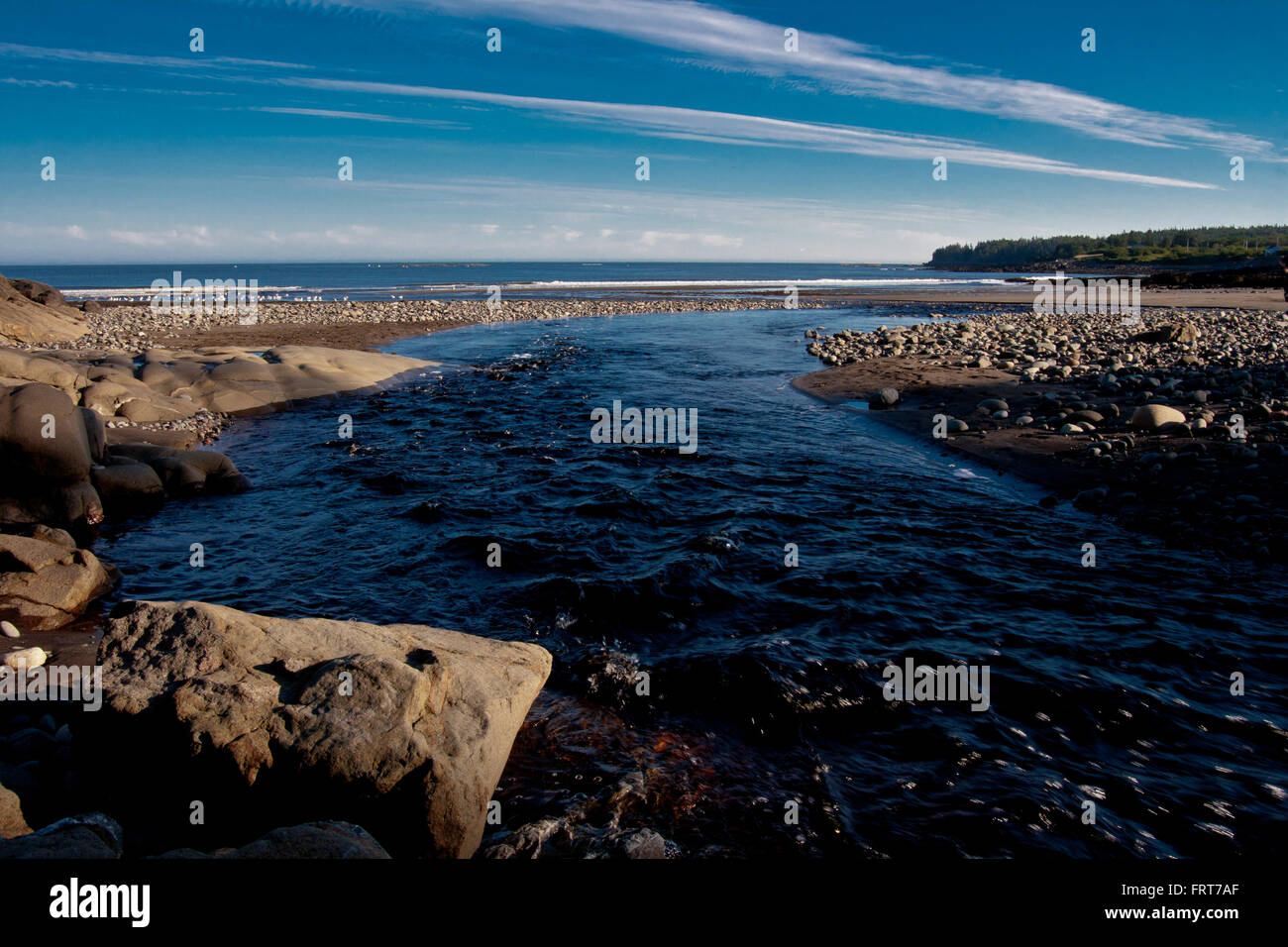 Tide going out at Deep Cove Beach exposing the smooth stones of the ...