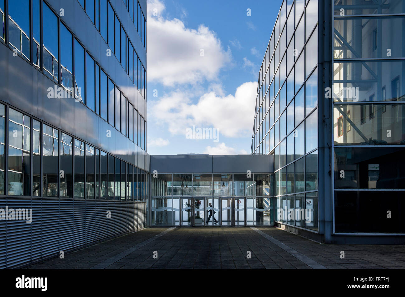 Man walking in a glass corridor between office buildings. Milton Keynes ...