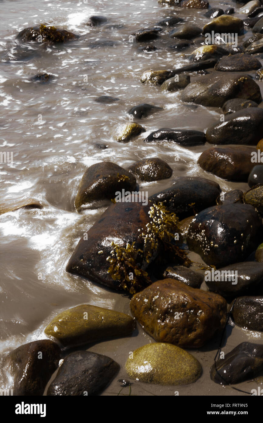 Silky water of the ocean dancing between the rocks along the shore ...