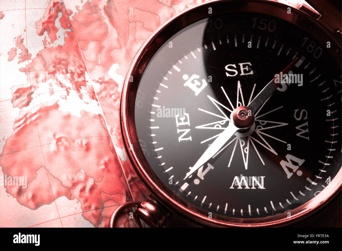Compass on map background in red toning Stock Photo - Alamy