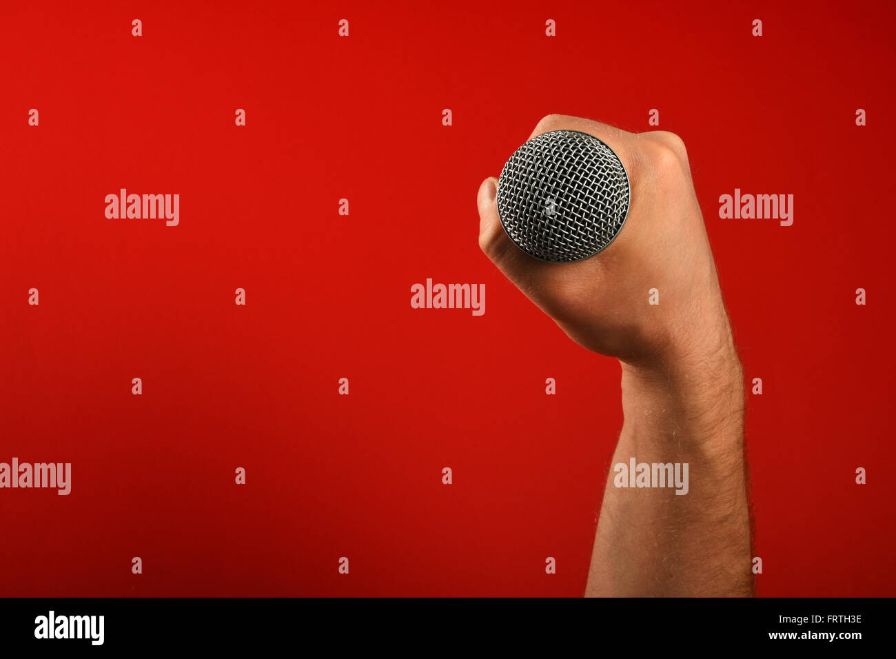 Man hand holding voice microphone in fist over red background, top view ...