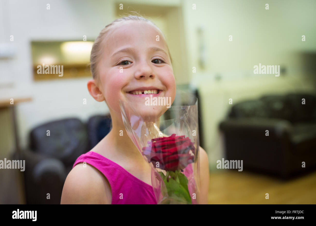 A young girl poses with a red rose following her grade 1 ballet ...