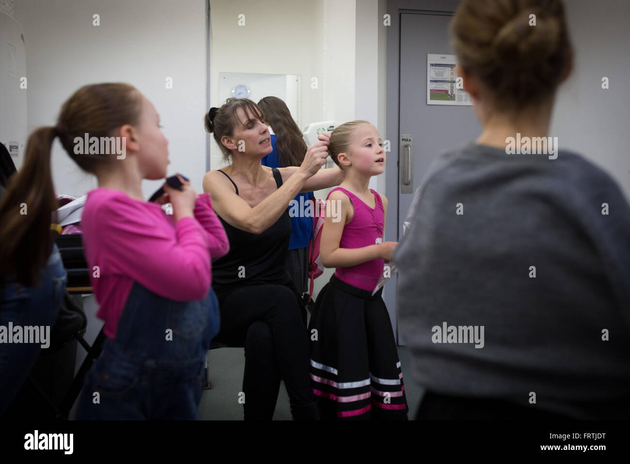 A ballet instructor prepares the hair of a student before her grade 1 ...