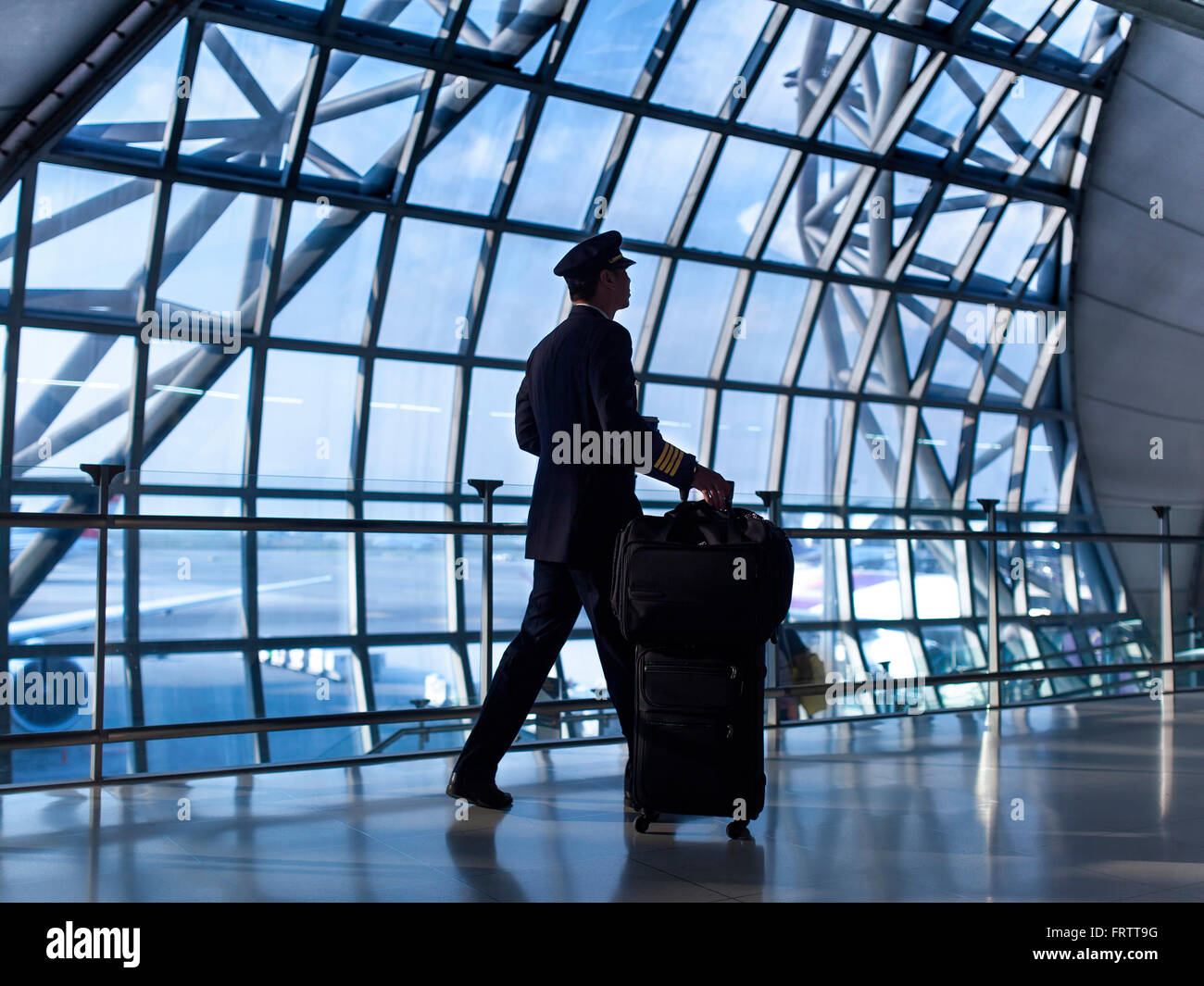 Pilot walking the airport terminal Stock Photo - Alamy
