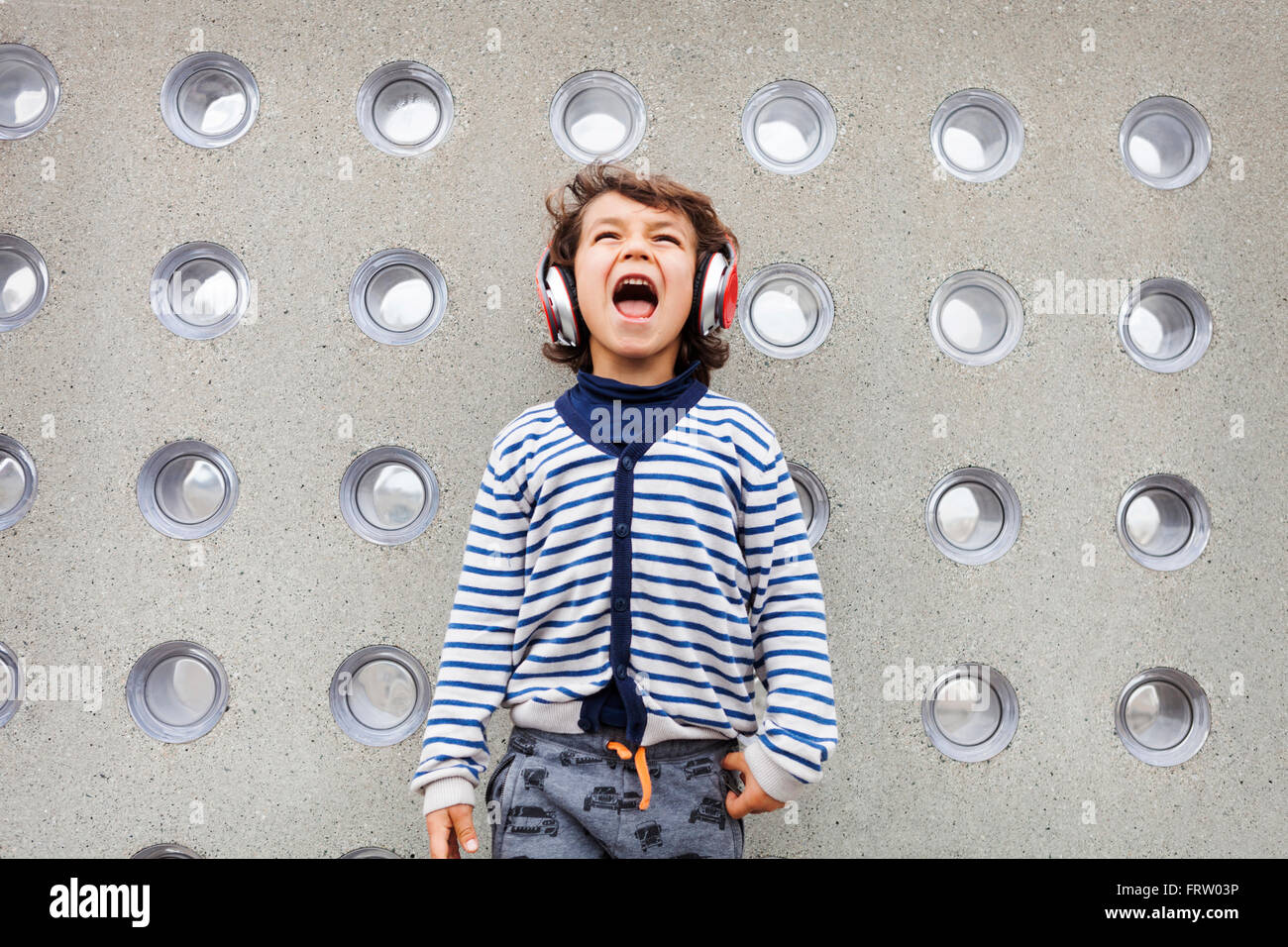 Portrait of little boy singing while listening music with headphones ...
