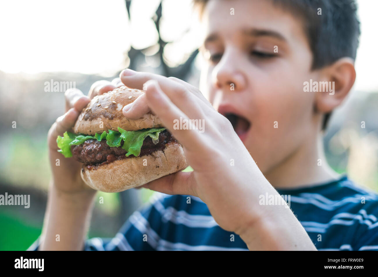 Boy eating hamburger, close-up Stock Photo - Alamy