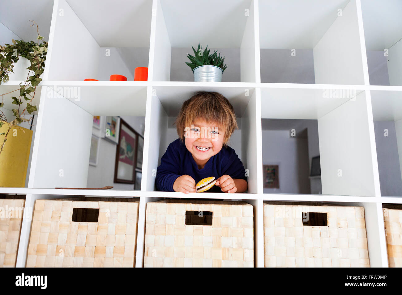Portrait of happy boy in shelf Stock Photo - Alamy