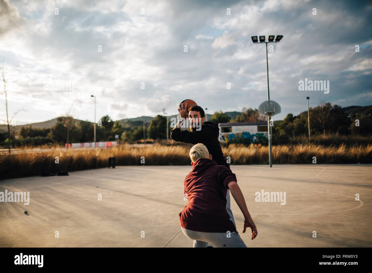 Two young men playing basketball on an outdoor court Stock Photo - Alamy