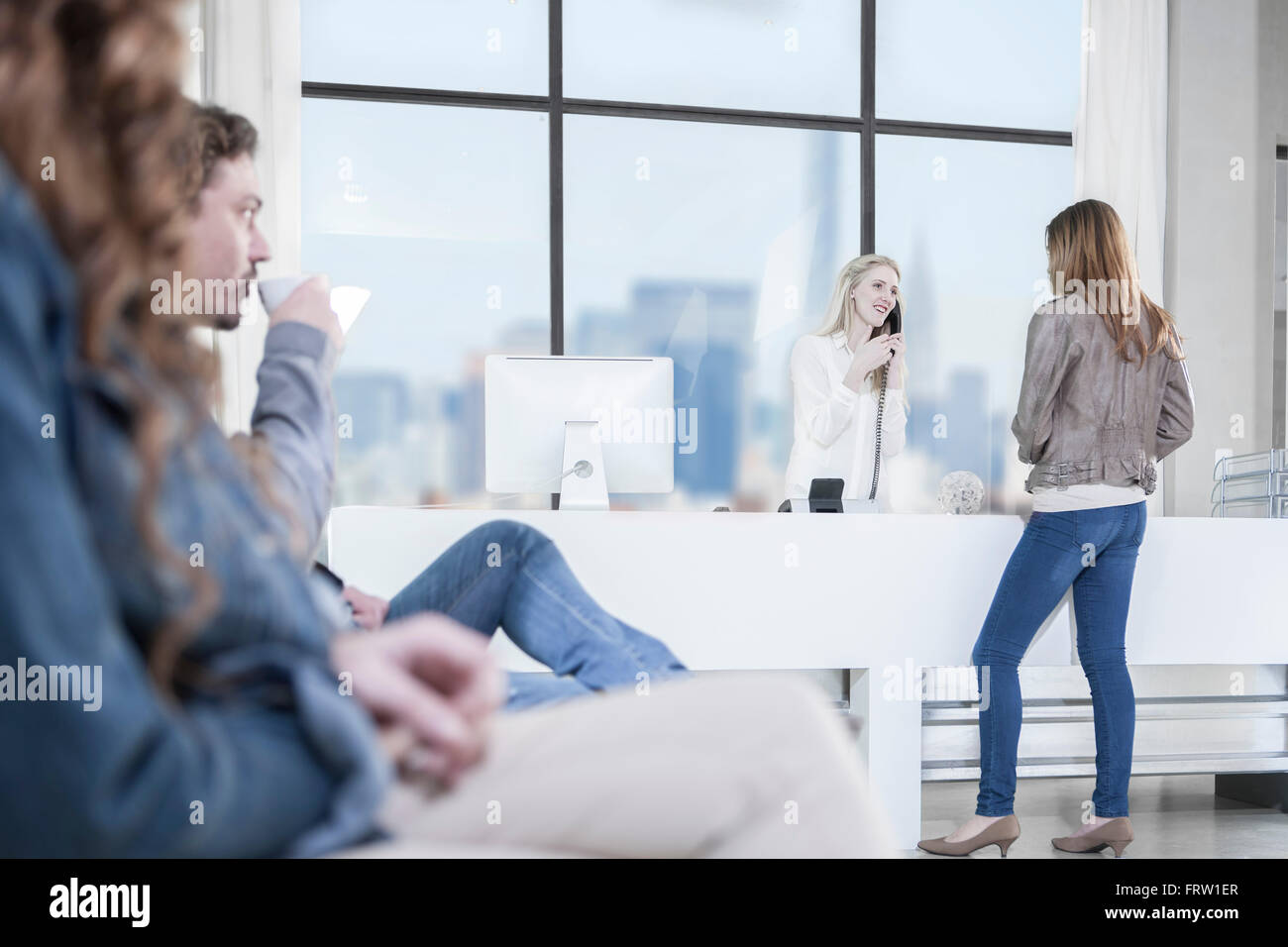 Office receptionist on the phone talking to guest Stock Photo - Alamy