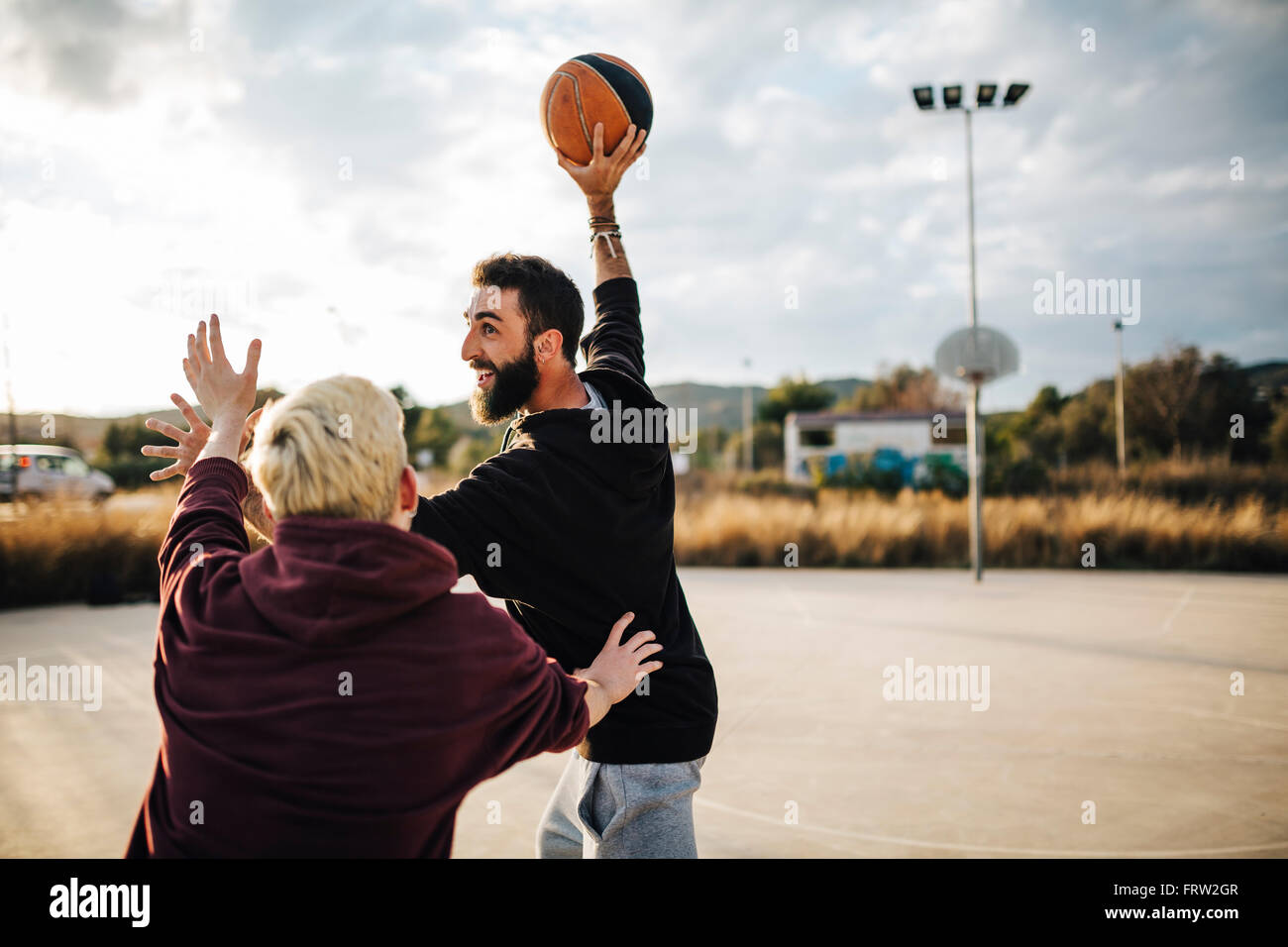 Two young men playing basketball on an outdoor court Stock Photo - Alamy