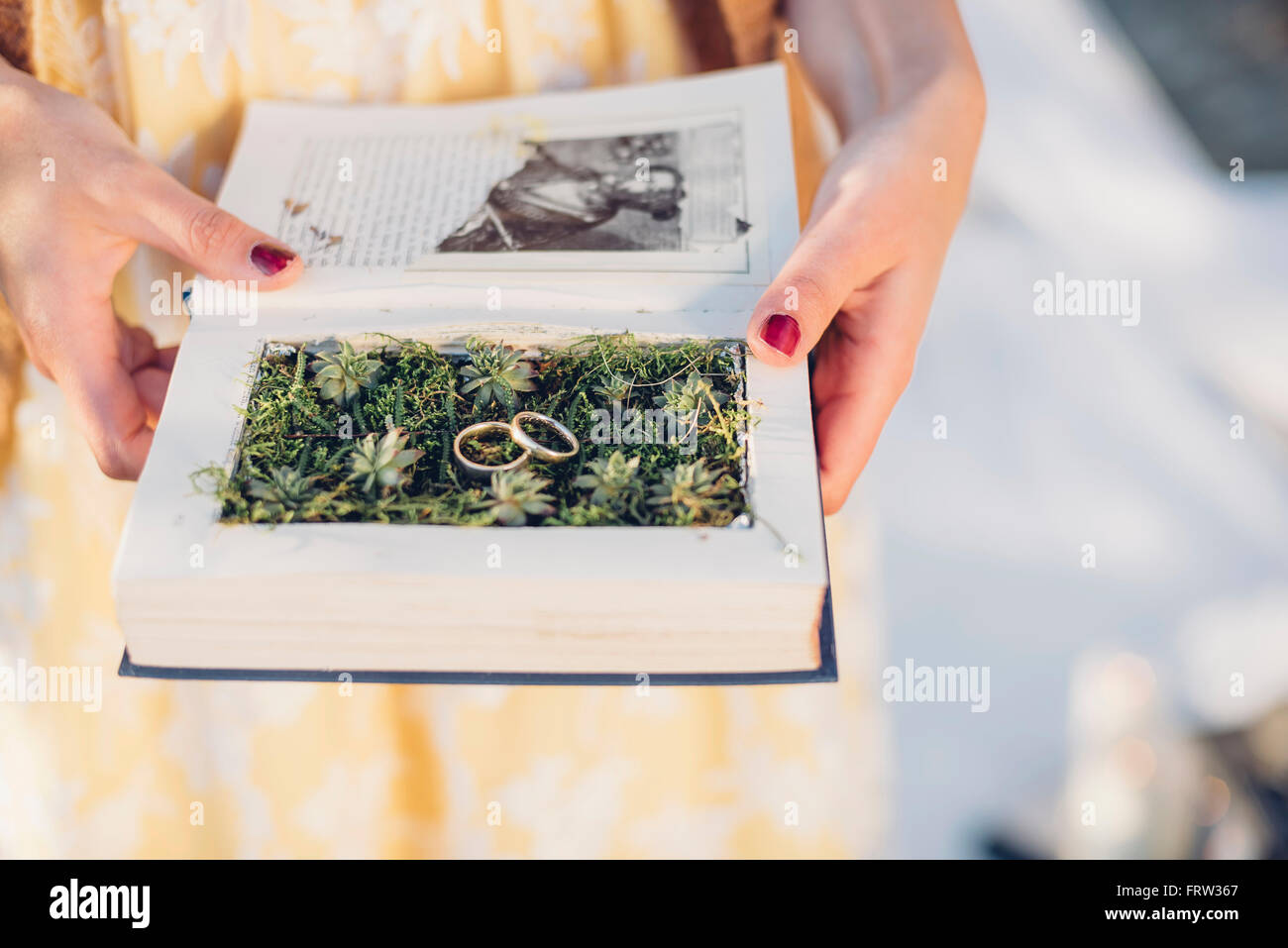Woman's hands holding prepared book with two wedding rings lying on ...