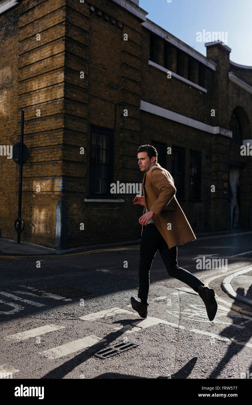 Young man in a hurry crossing urban street Stock Photo - Alamy
