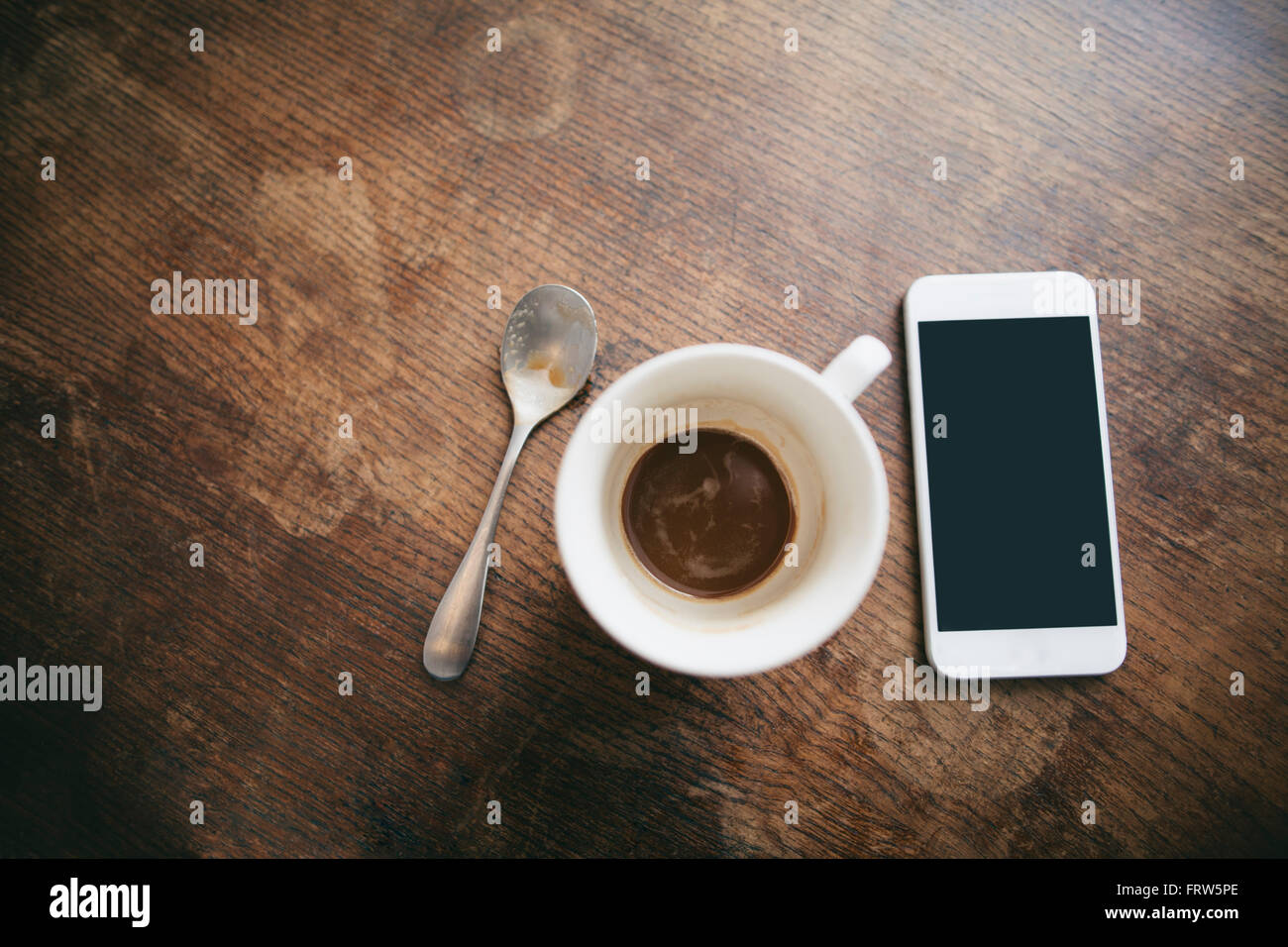 Coffee cup with remains of coffee, spoon and smartphone on wood Stock ...