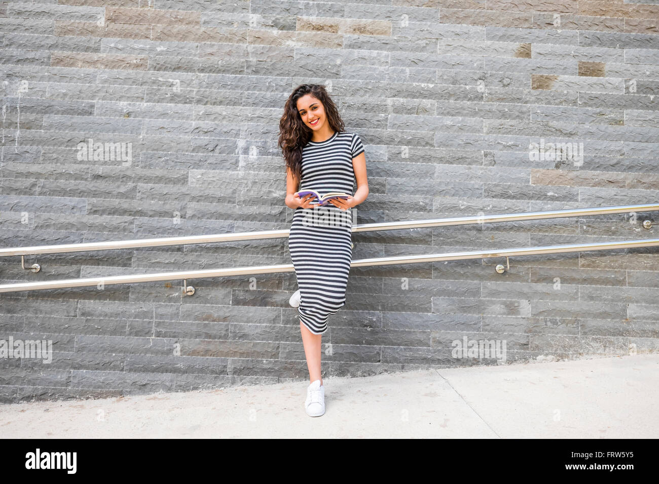 Portrait of smiling teenage girl with book wearing striped dress Stock ...