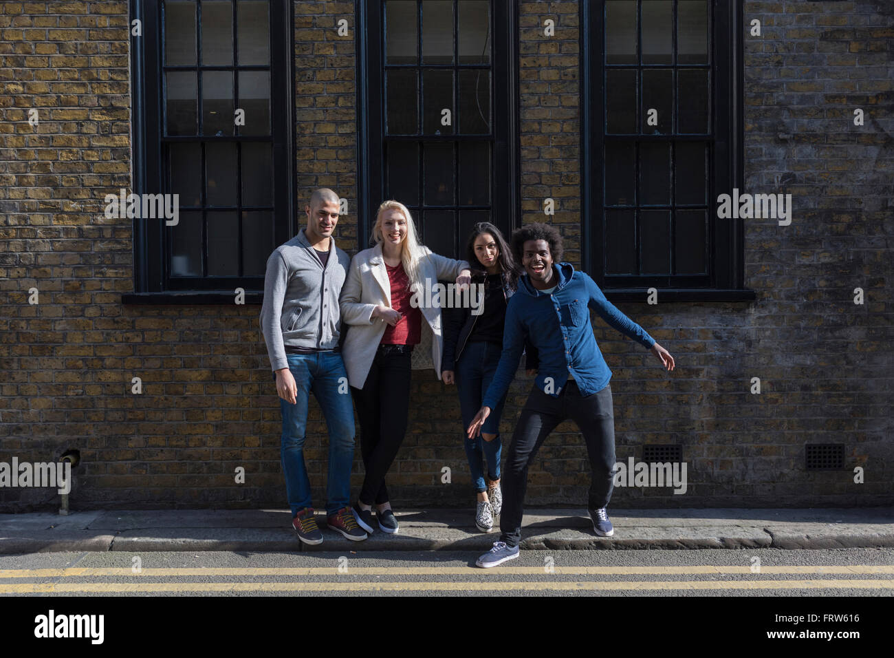 Group of happy friends posing in front of brick building Stock Photo ...