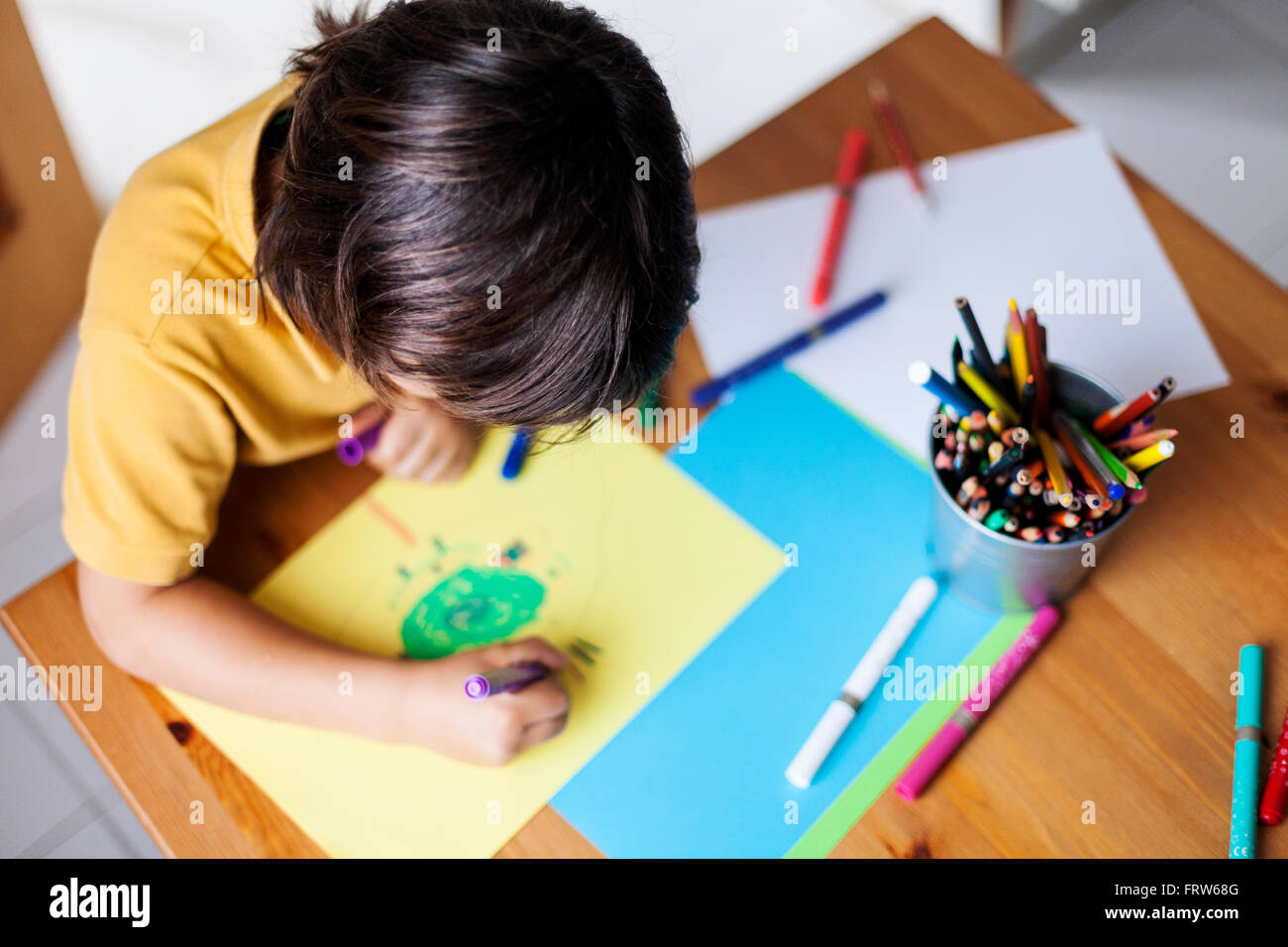 Little boy drawing on yellow paper Stock Photo - Alamy