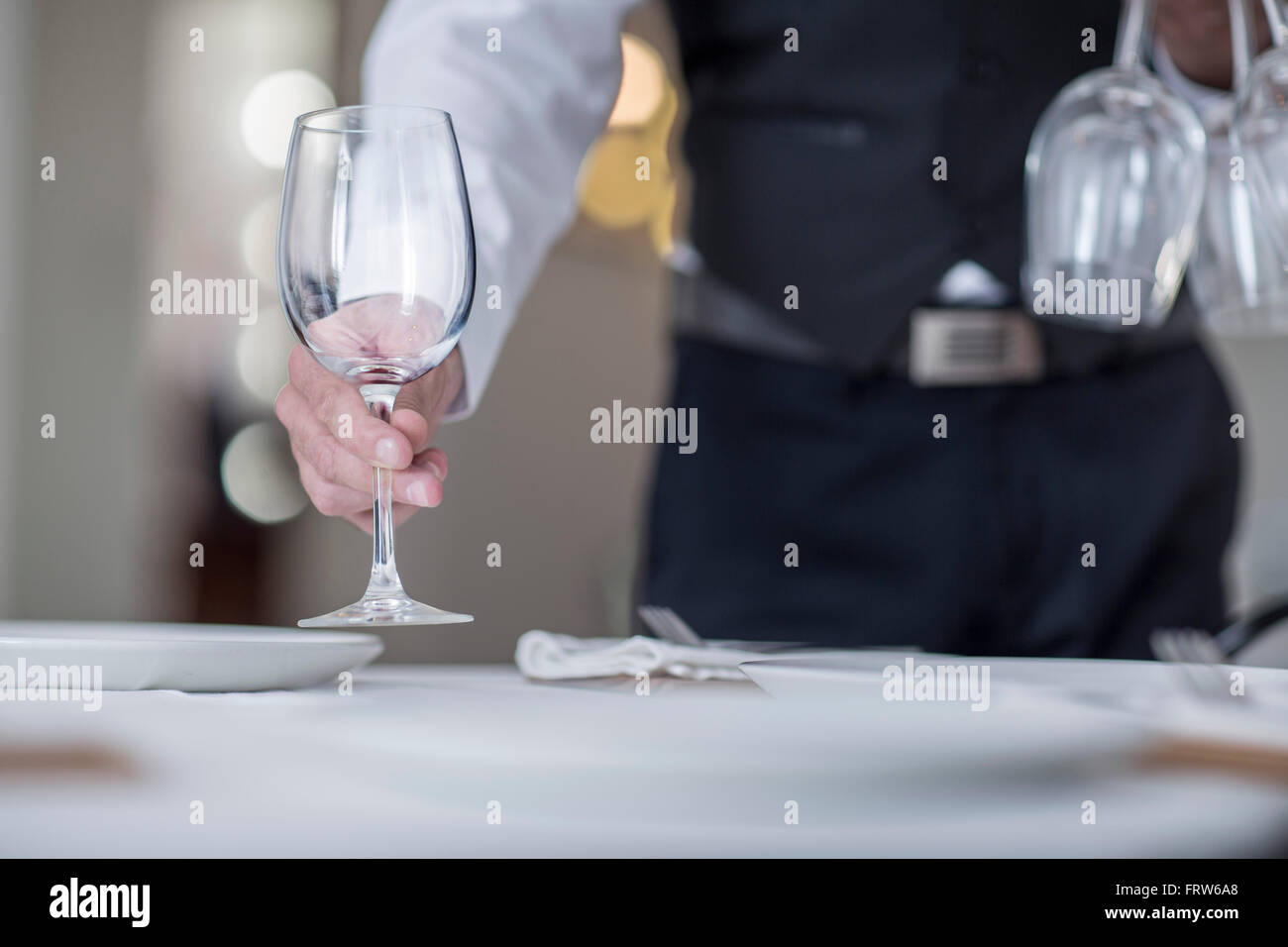 Waiter placing wine glasses on restaurant table Stock Photo - Alamy