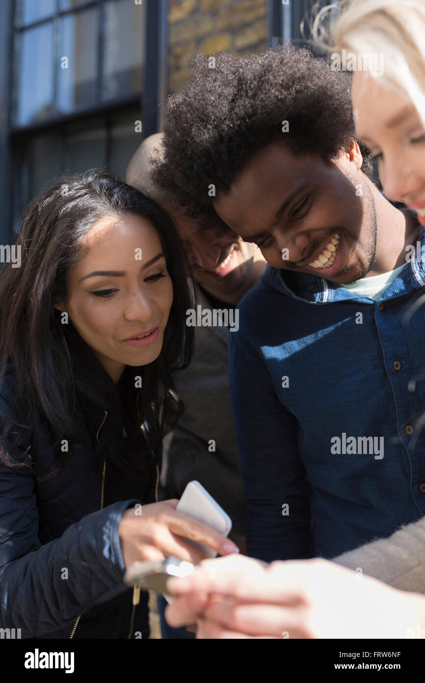 Group of happy friends looking at cell phone Stock Photo - Alamy