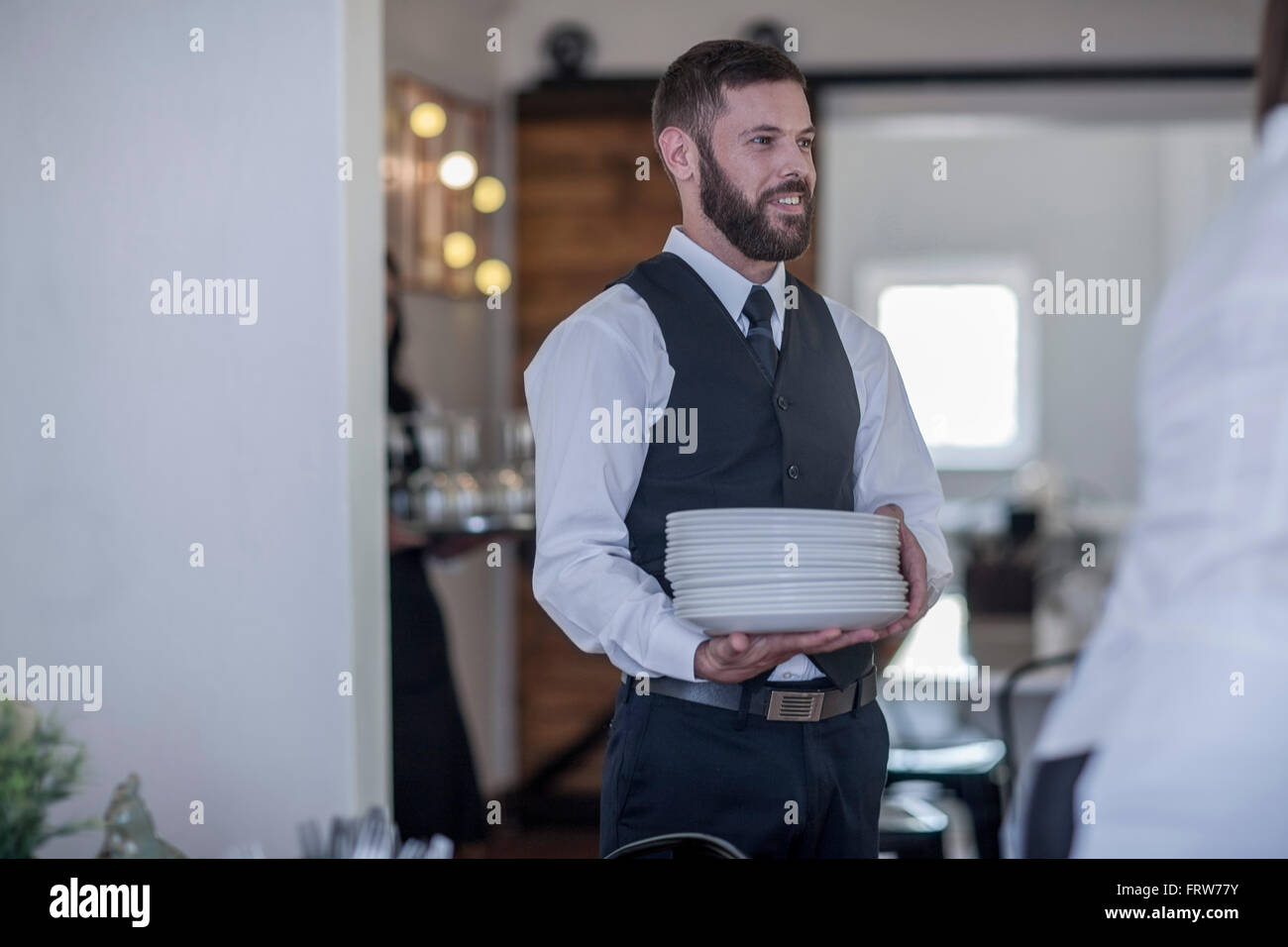 Waiter carrying stack of plates Stock Photo - Alamy