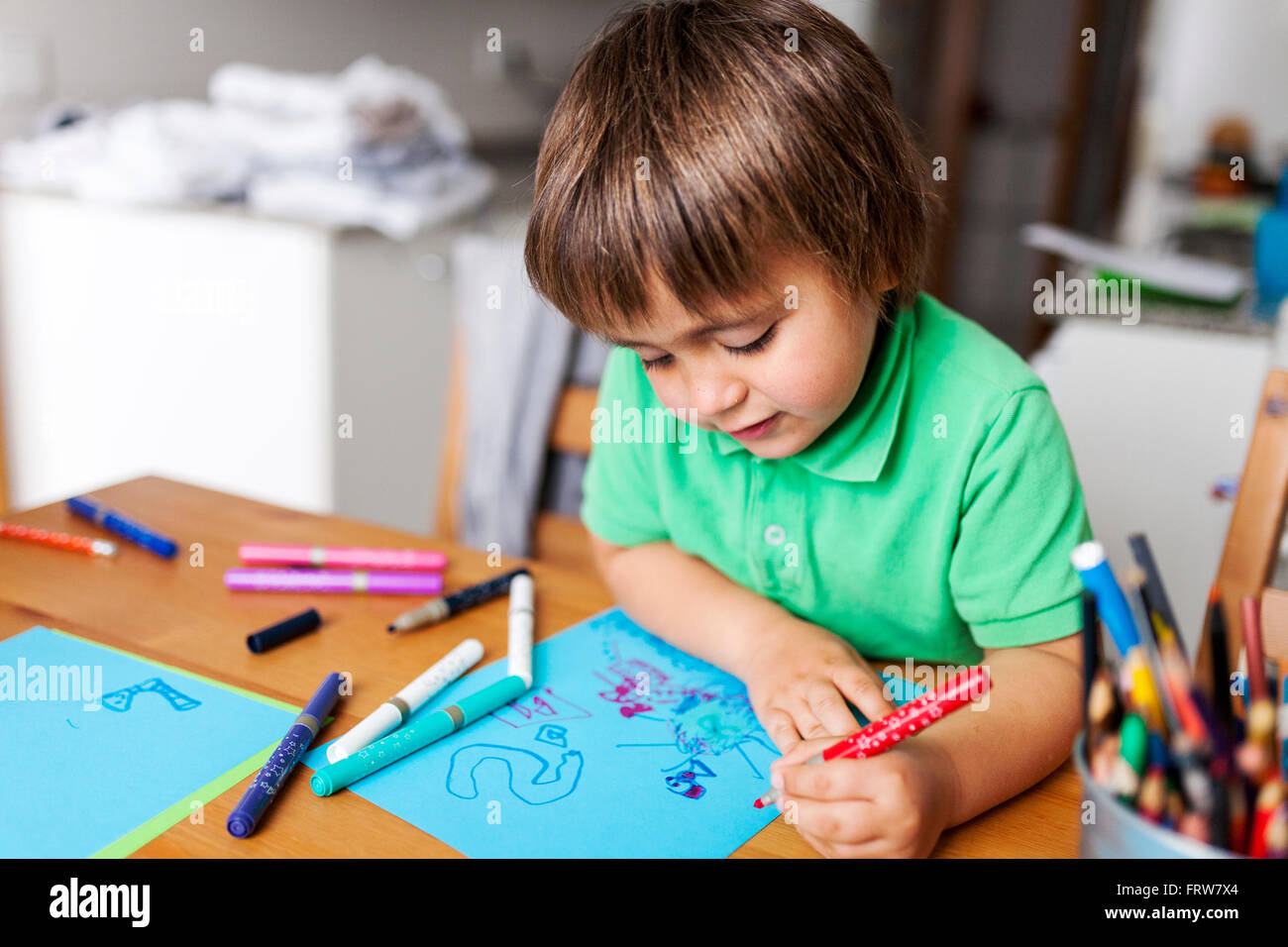 Little boy drawing on blue paper at home Stock Photo - Alamy