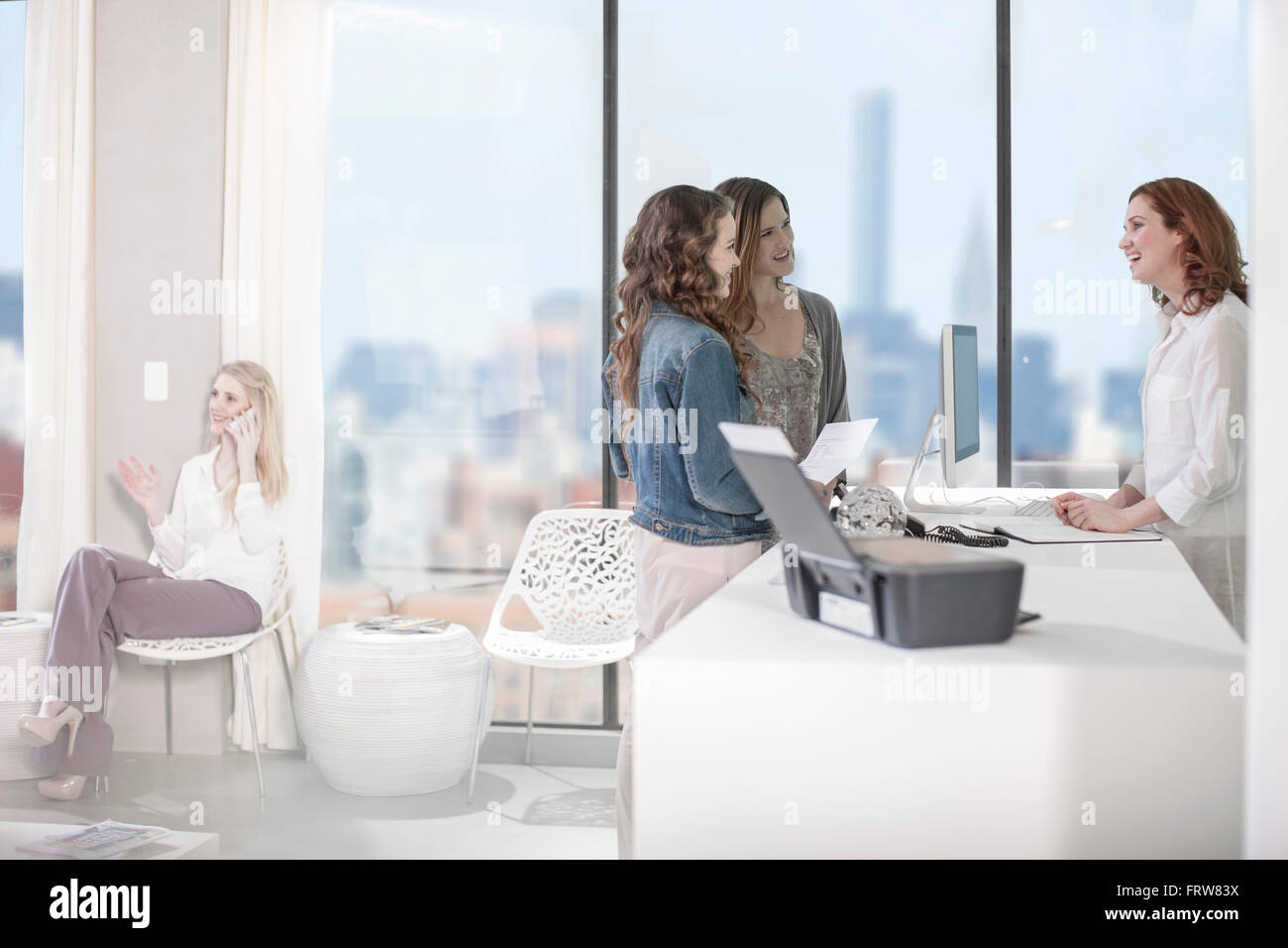 Office receptionist talking to guests Stock Photo - Alamy