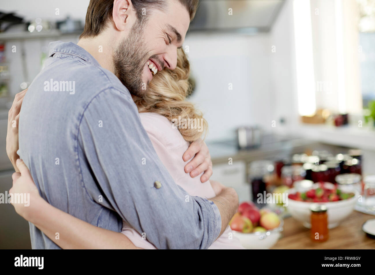 Happy couple hugging in kitchen Stock Photo - Alamy