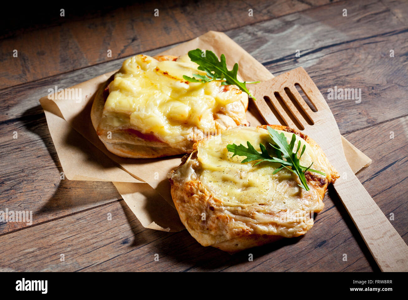 Two mini pizzas and a pancake turner on baking paper and wood Stock ...