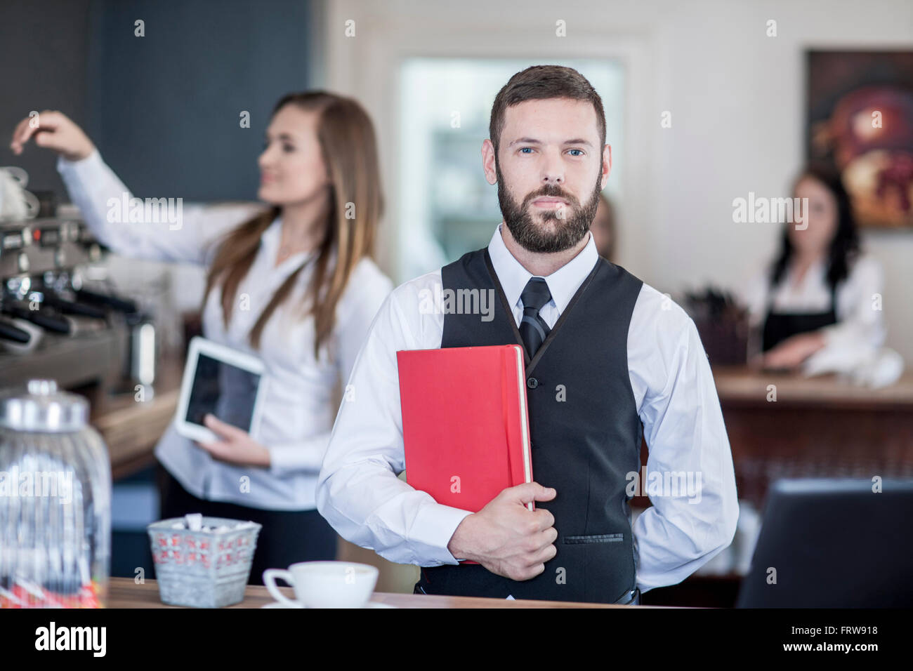 Restaurant manager holding red notebook, looking at camera Stock Photo ...