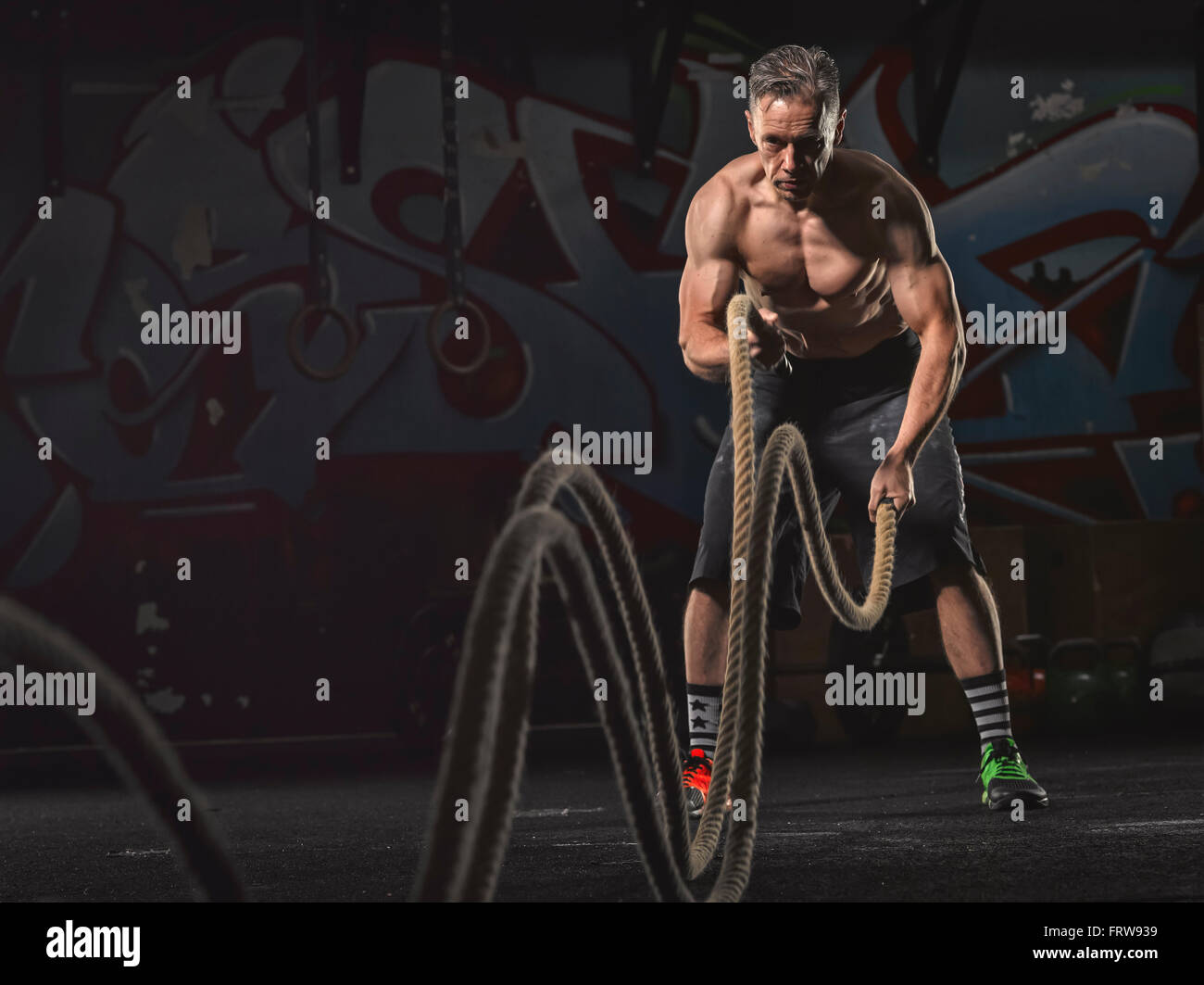 Mature crossfit athlete exercising with ropes Stock Photo - Alamy