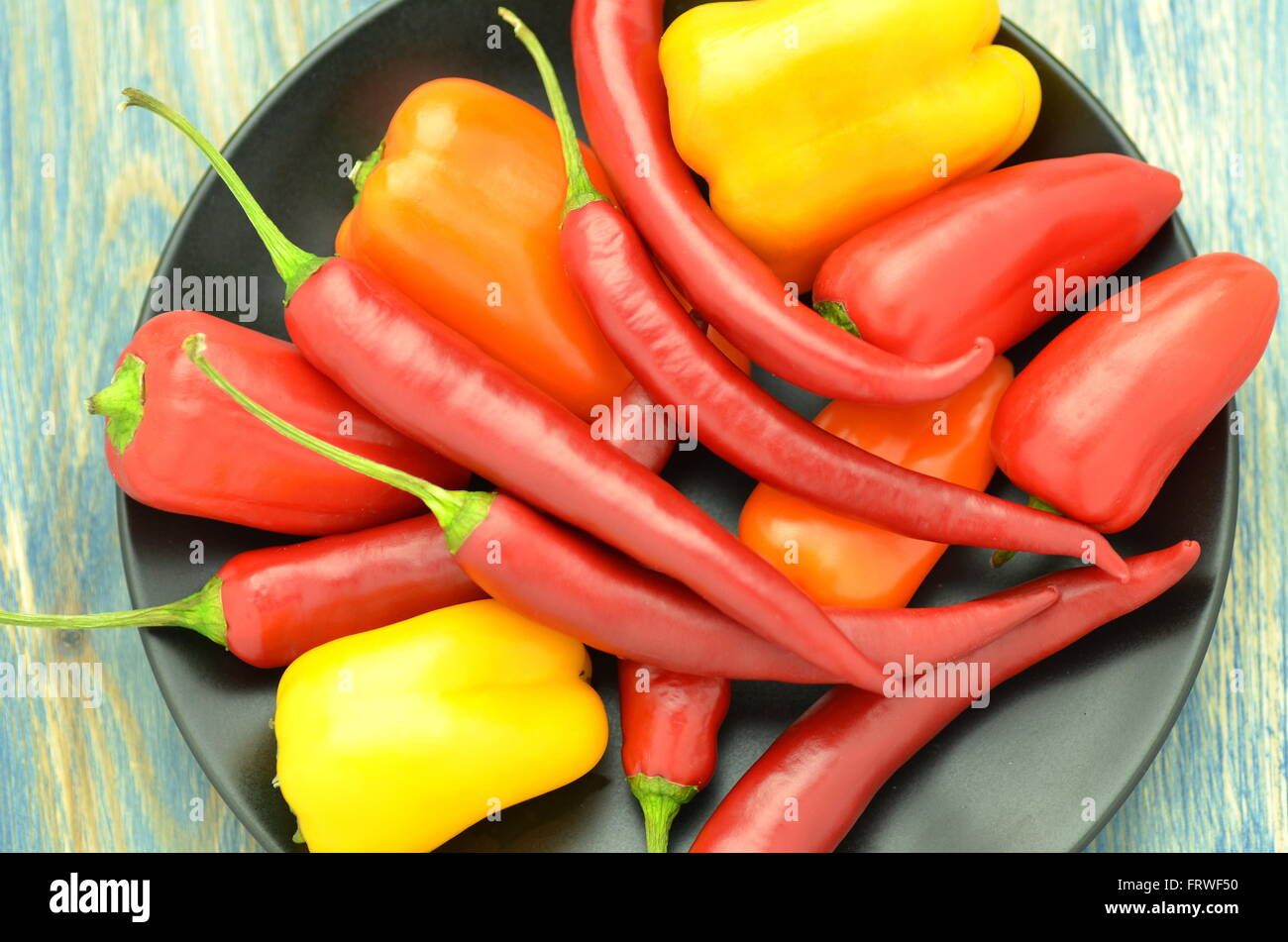 variety of different peppers on black plate Stock Photo - Alamy
