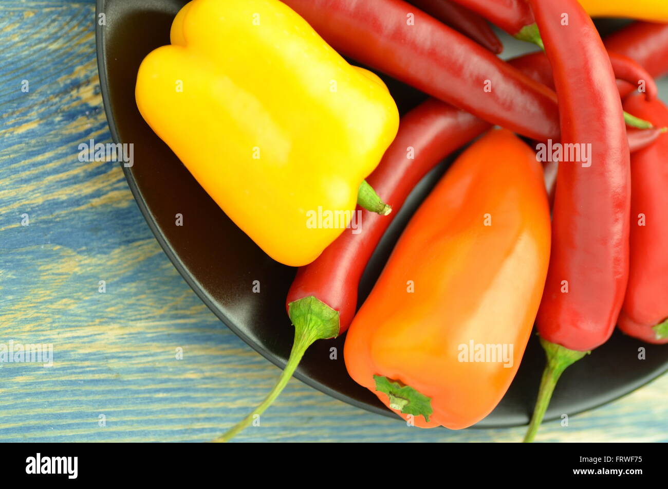variety of different peppers on black plate Stock Photo - Alamy
