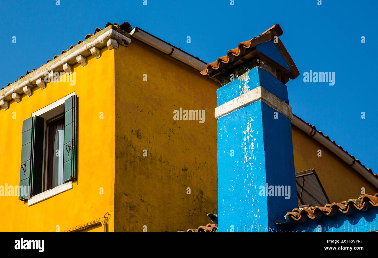 Colorful yellow house with blue chimney and blue sky in Burano, Venice ...