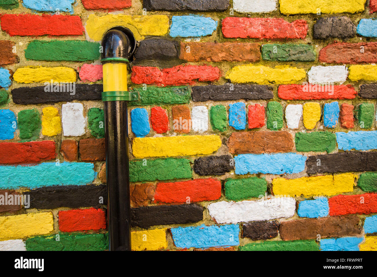 Colorful stone brick wall with painted pipeline on left side of picture ...