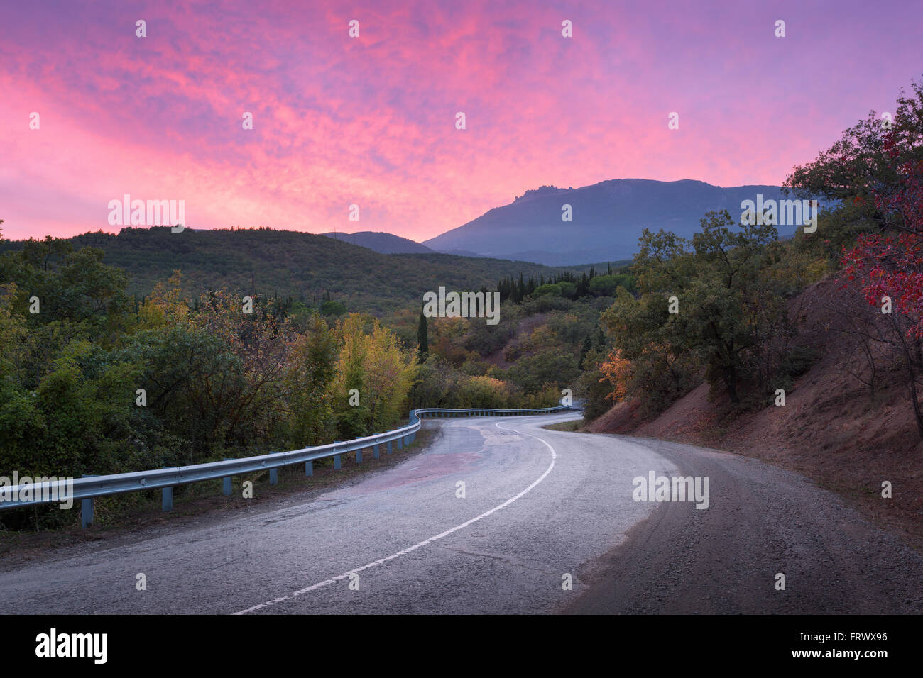 Mountain winding road passing through the forest with dramatic colorful ...