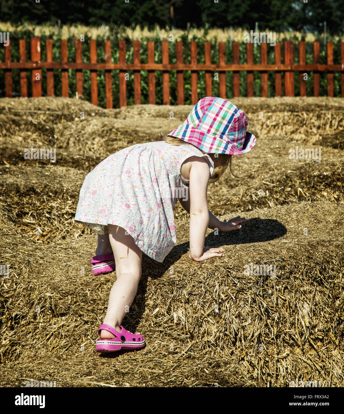 Little girl is climbing up on the haystack. Leisure activity Stock ...