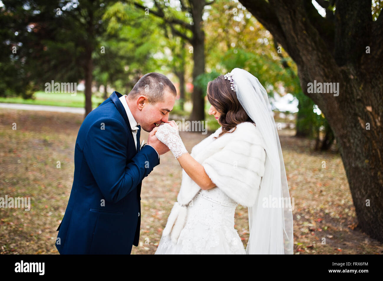 Close up portrait of kissing wedding couple, groom kiss hands of bride ...