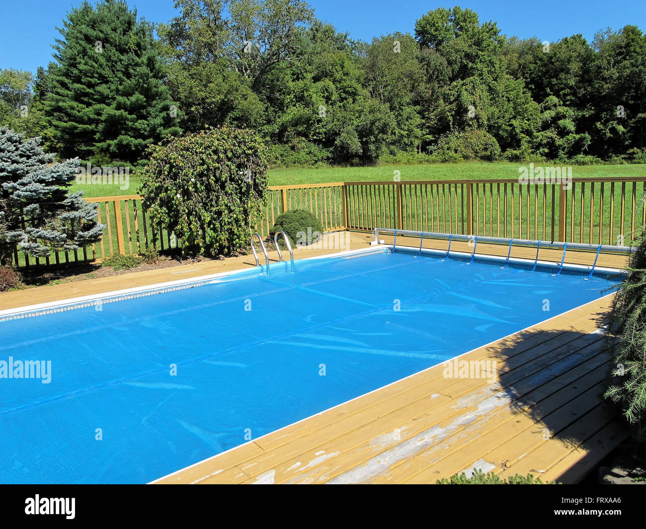 Suburban pool with blue plastic roll out cover Stock Photo - Alamy