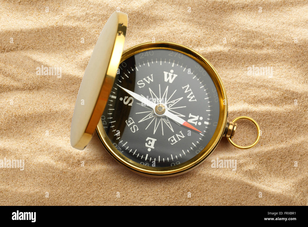 Golden vintage compass on sand background closeup Stock Photo - Alamy
